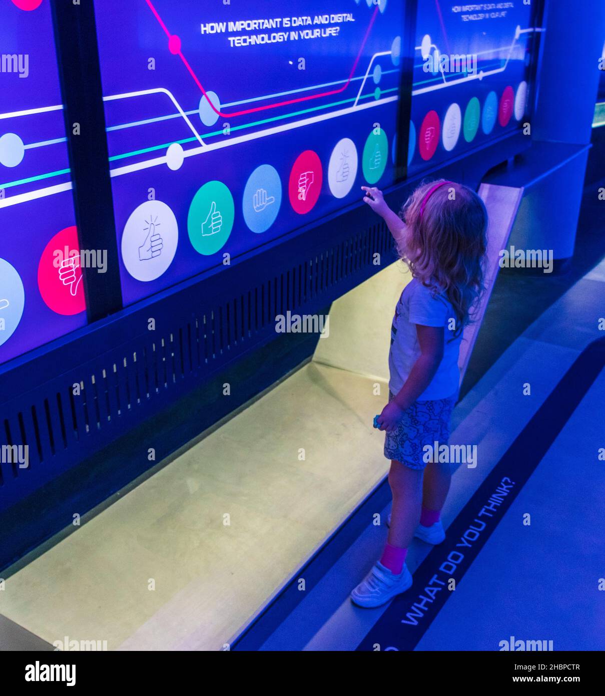 Little girl plays with buttons of the interactive wall Stock Photo - Alamy