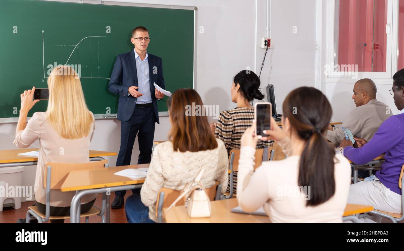 Professor explaining function graph to adult students in auditorium ...