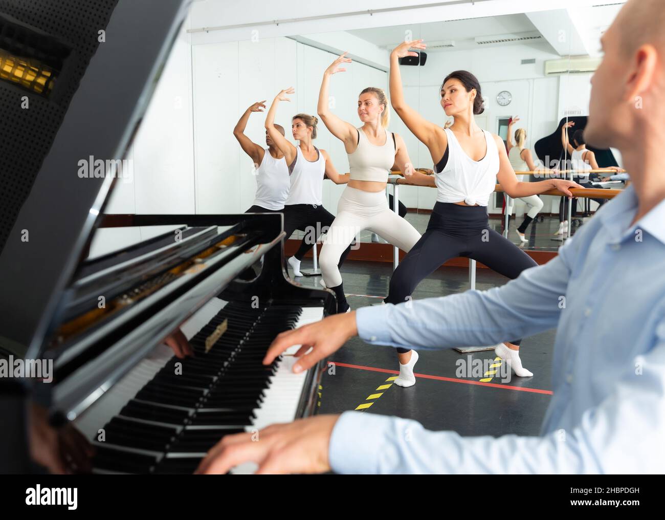 dancers doing exercises on stretching ballet barre under live music ...