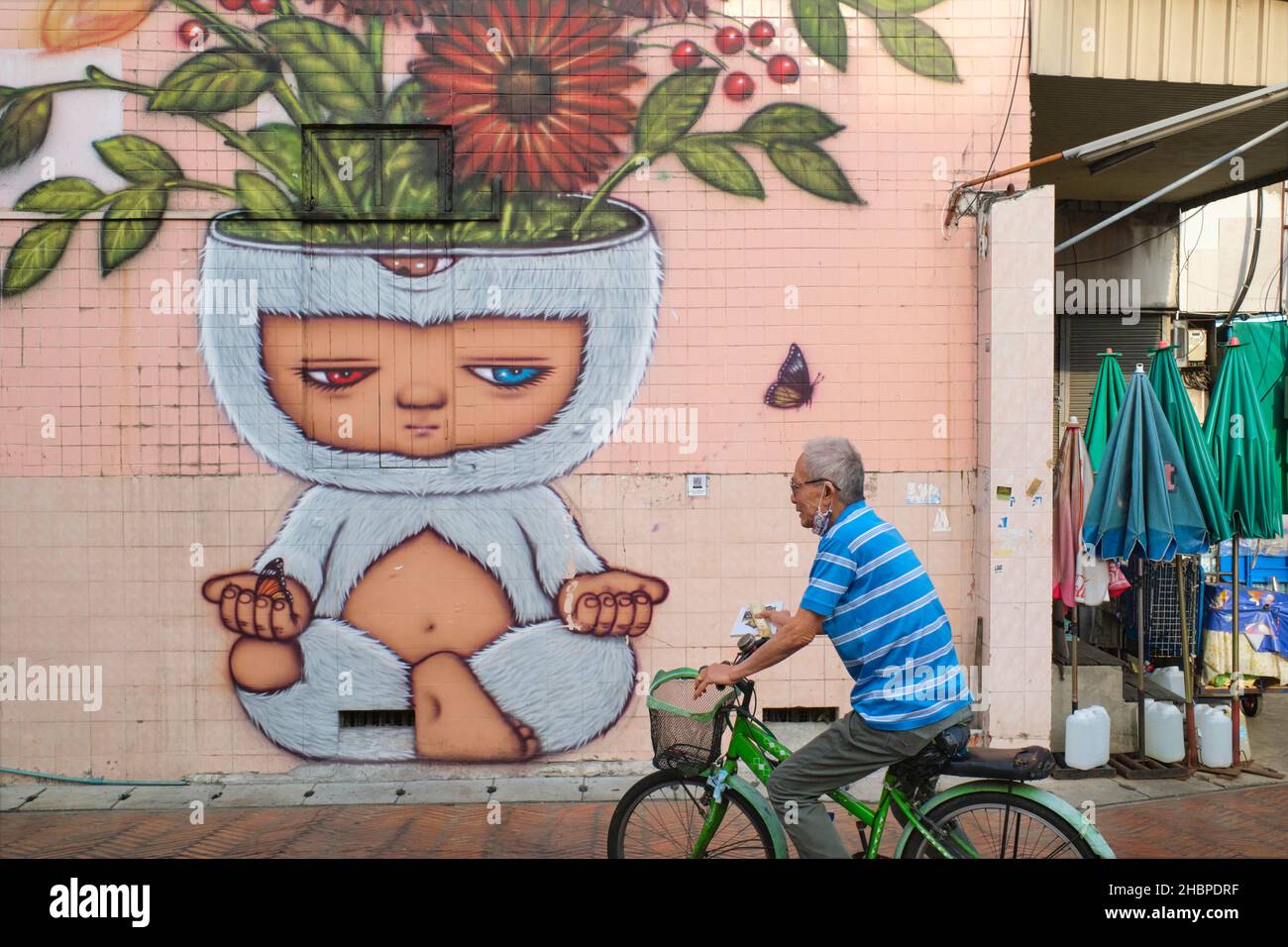 A cyclist passes a wall painting by Thai artist Alex Face featuring his ...