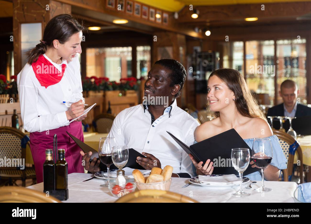 Positive young couple making order at restaurant Stock Photo - Alamy