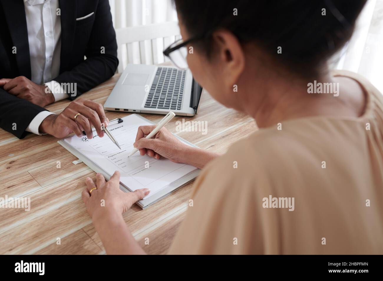 Insurance agent showing senior customer where to sign claim form Stock ...
