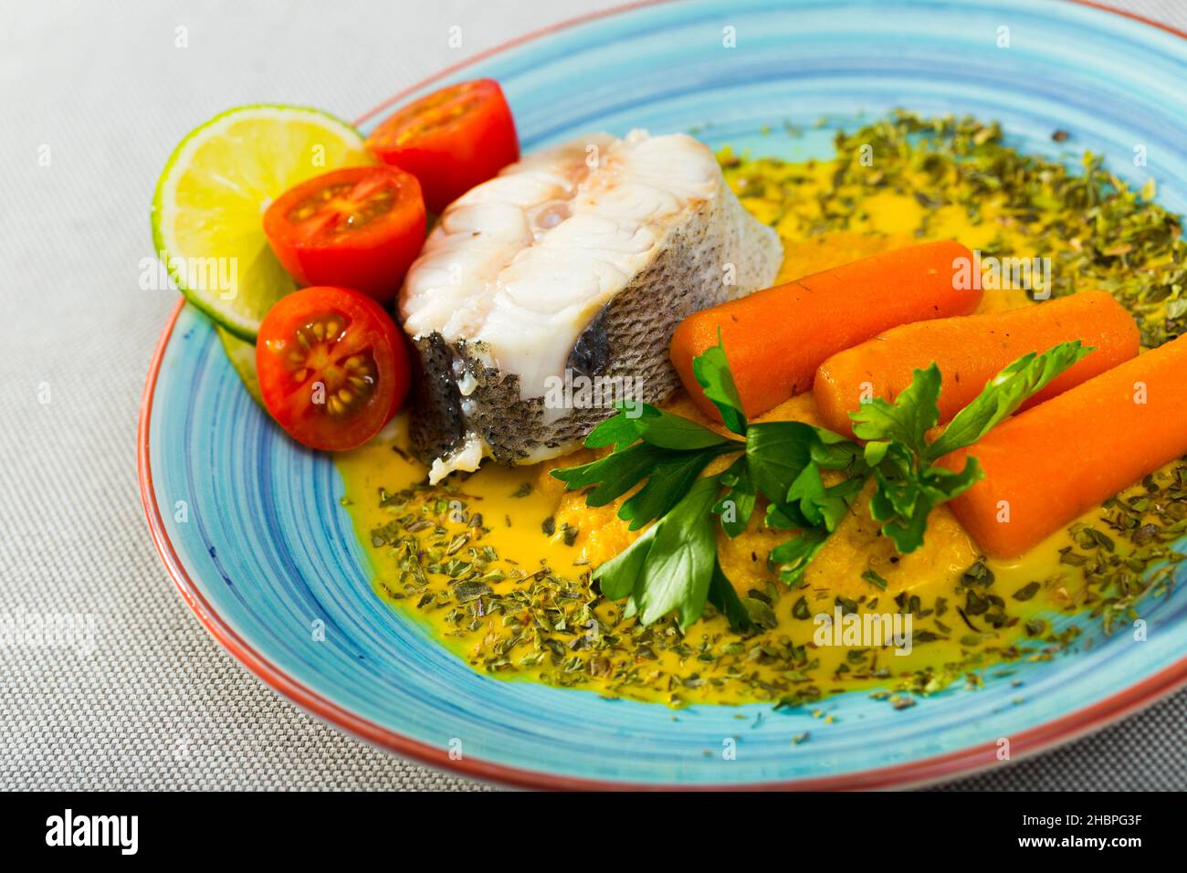 Steamed hake by served with vegetable pate, boiled carrots, lemon and ...