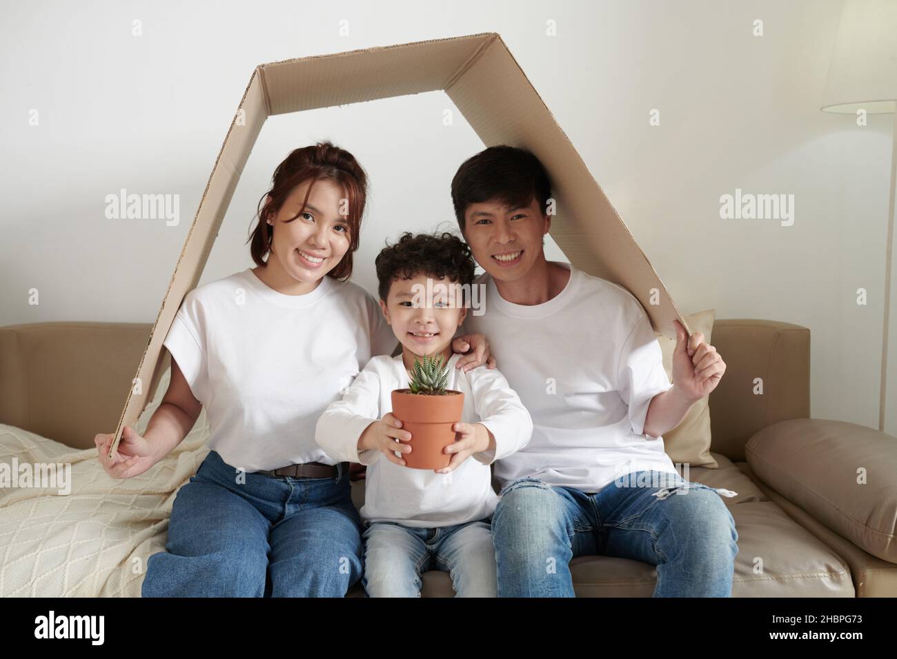 Father, mother and little son with cactus in pot sitting under ...