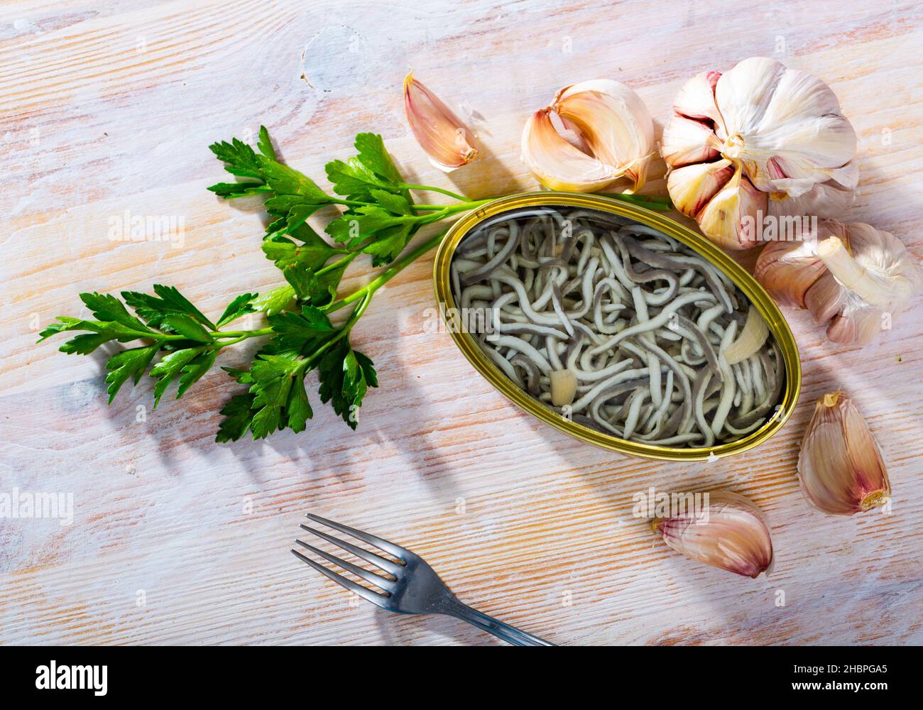 Tasty pickled eels on background garlic and greens at table Stock Photo ...