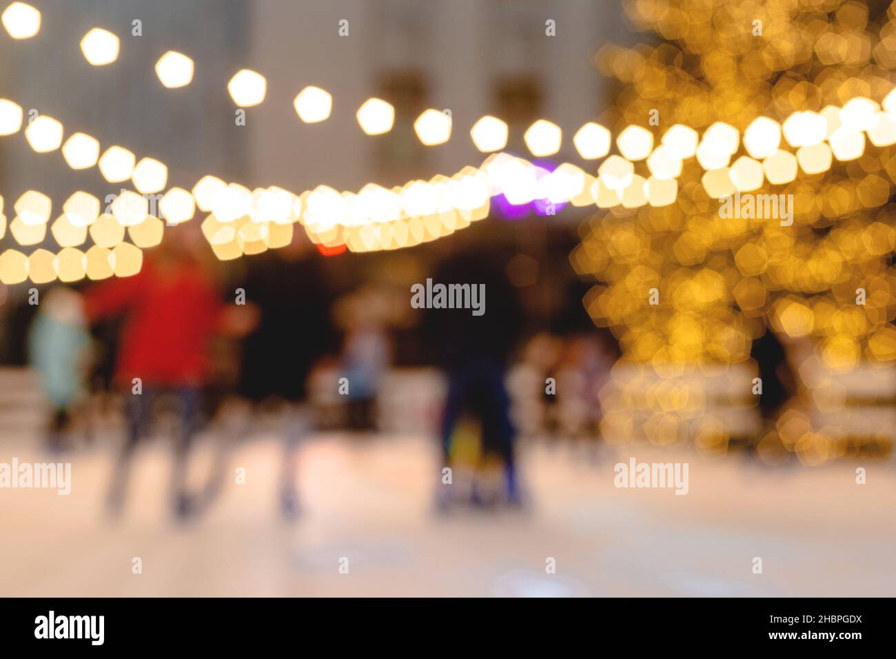 People ride skating rink on background of christmas tree in light ...