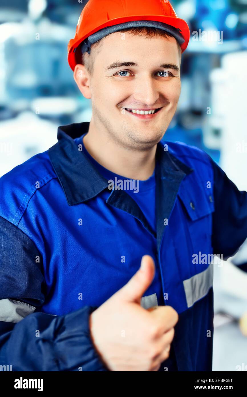 Young engineer in helmet shows thumbs up. Thumbs up. Great mood and ...