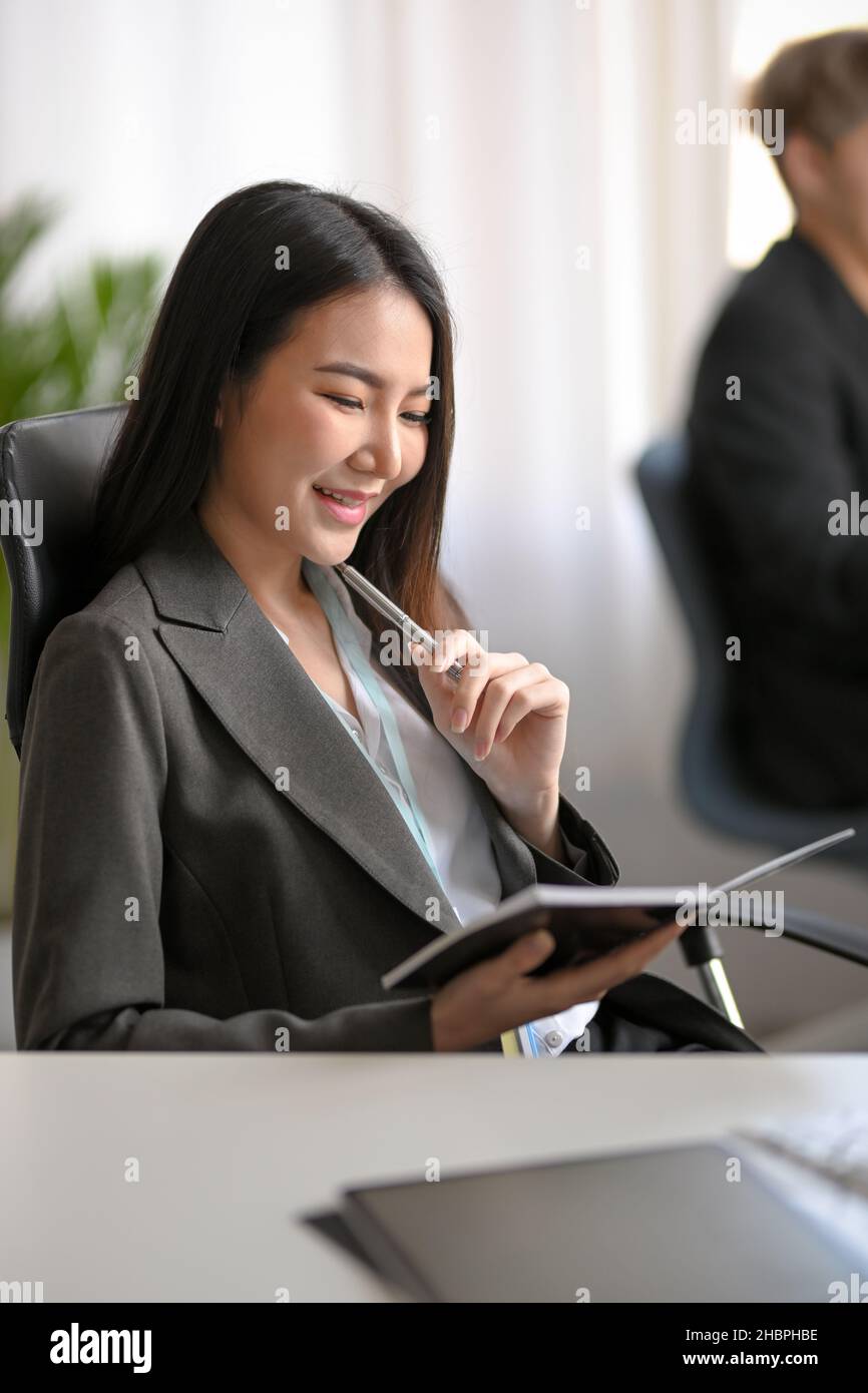 Beautiful female employee reading a book, checking her plans on her ...