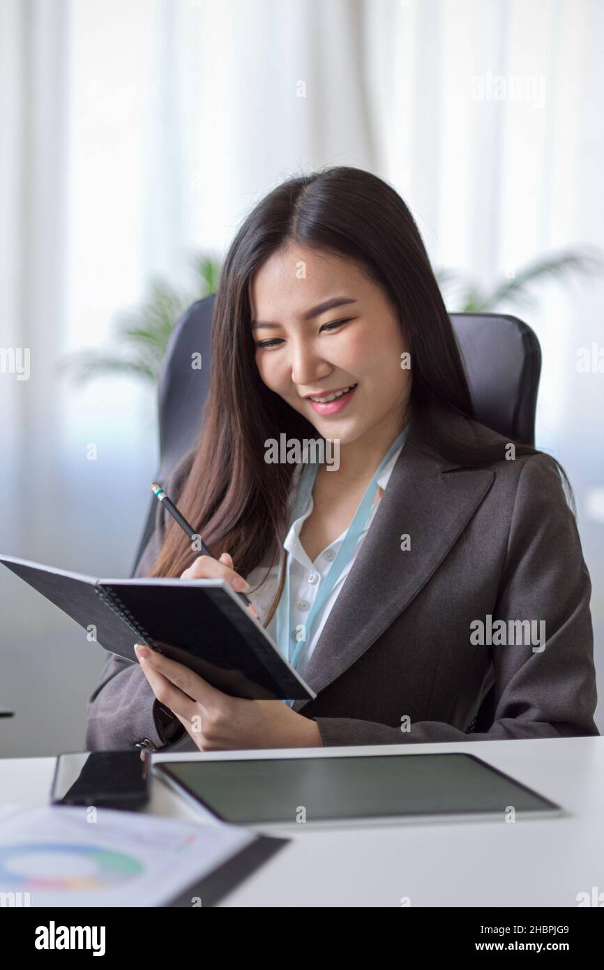 Portrait of an elegant female boss reading a book, checking some ...