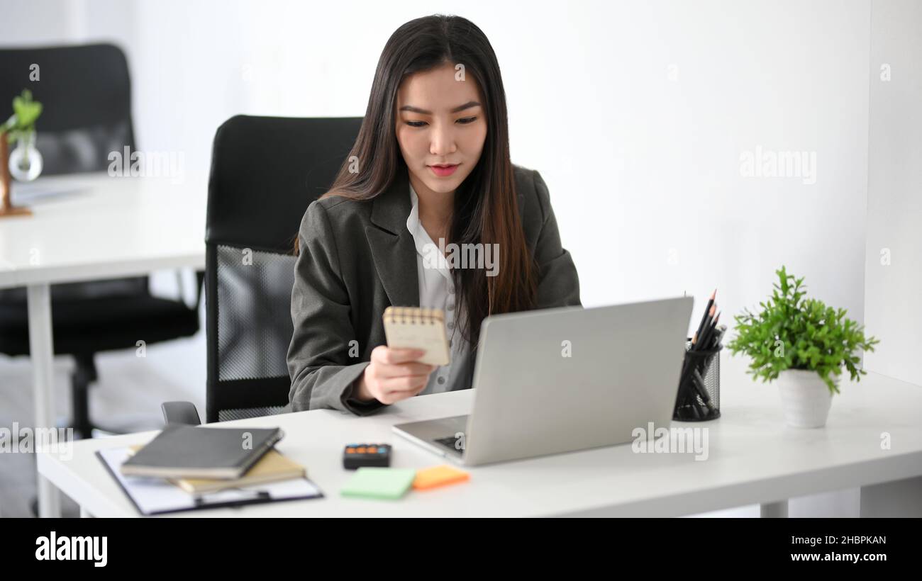 Beautiful Asian young assistant working on laptop computer, managing ...