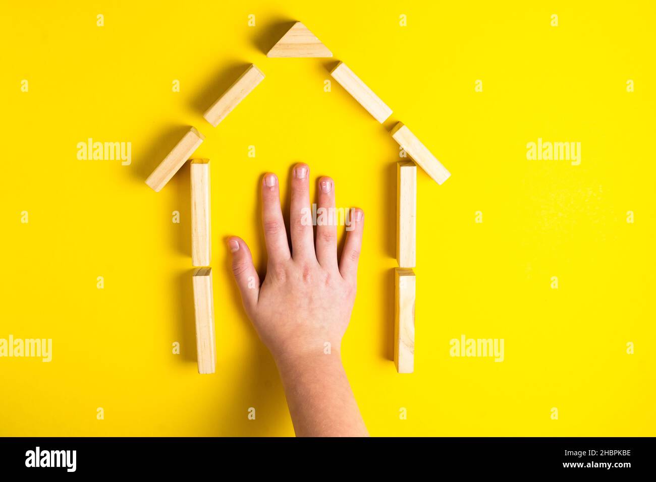 Top view of child's hand close up building blocks showing a home, house ...