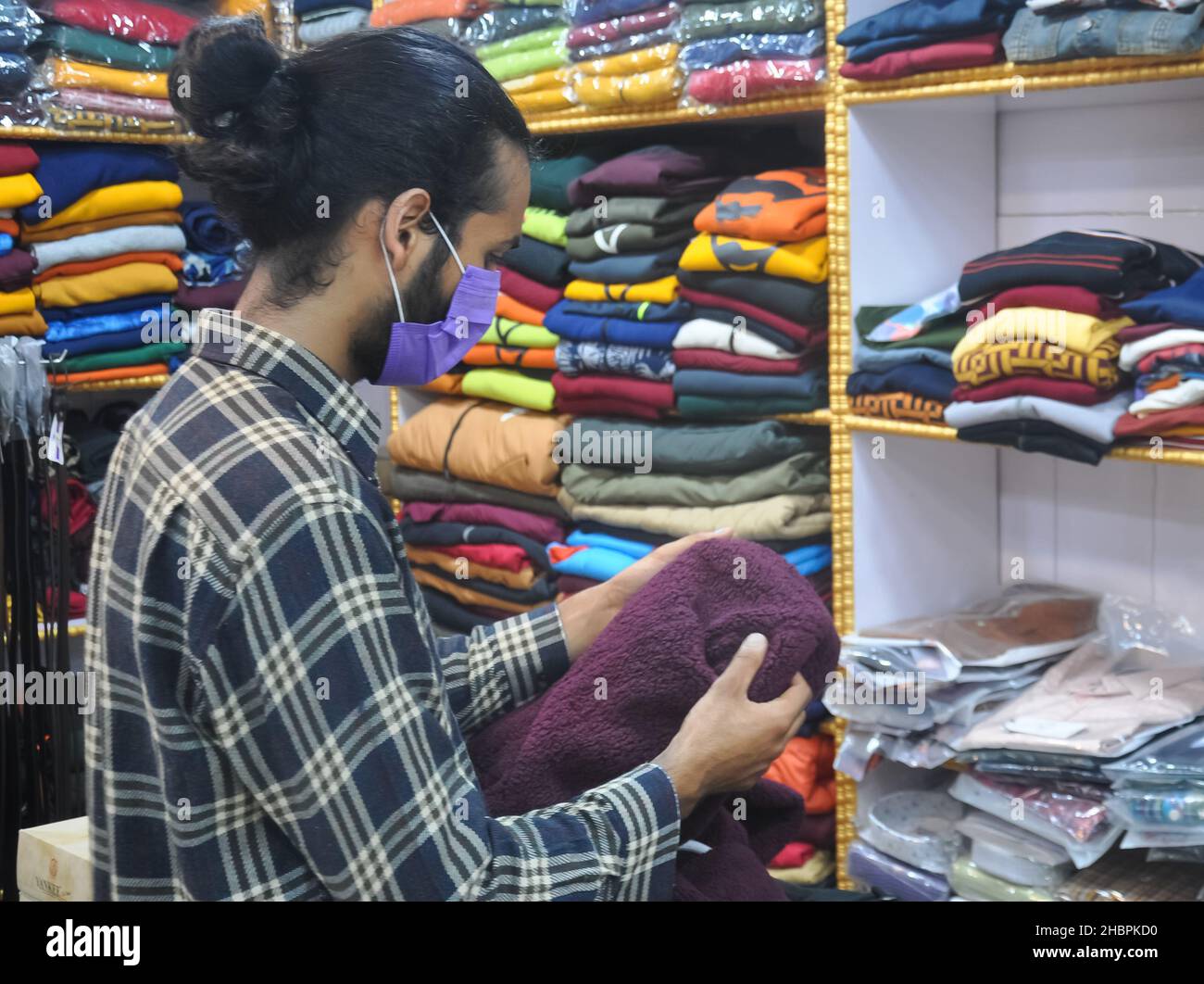 A good looking young guy wearing face mask looking at clothes to buy in ...