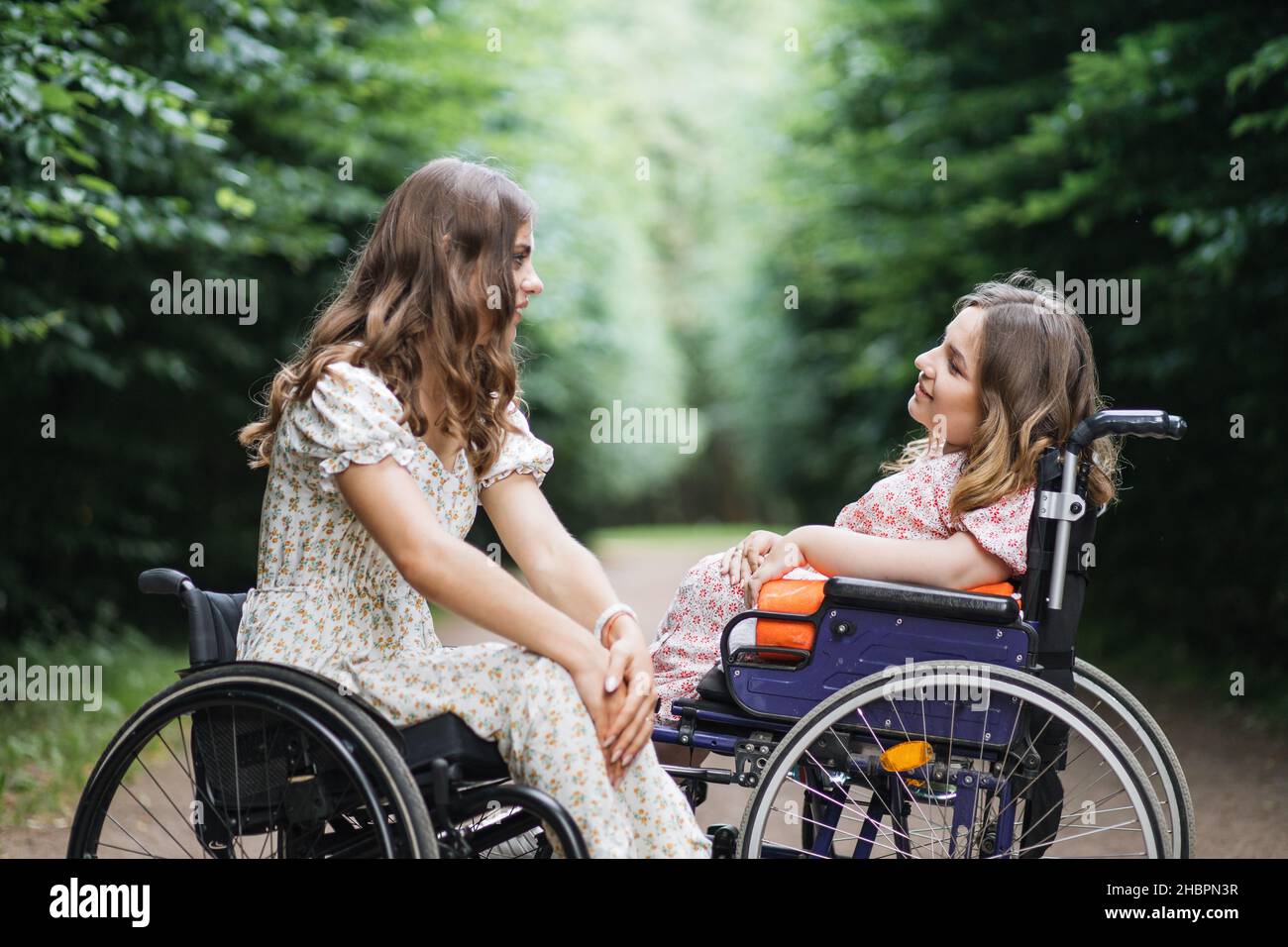 Positive female friends with physical disability chatting and smiling ...