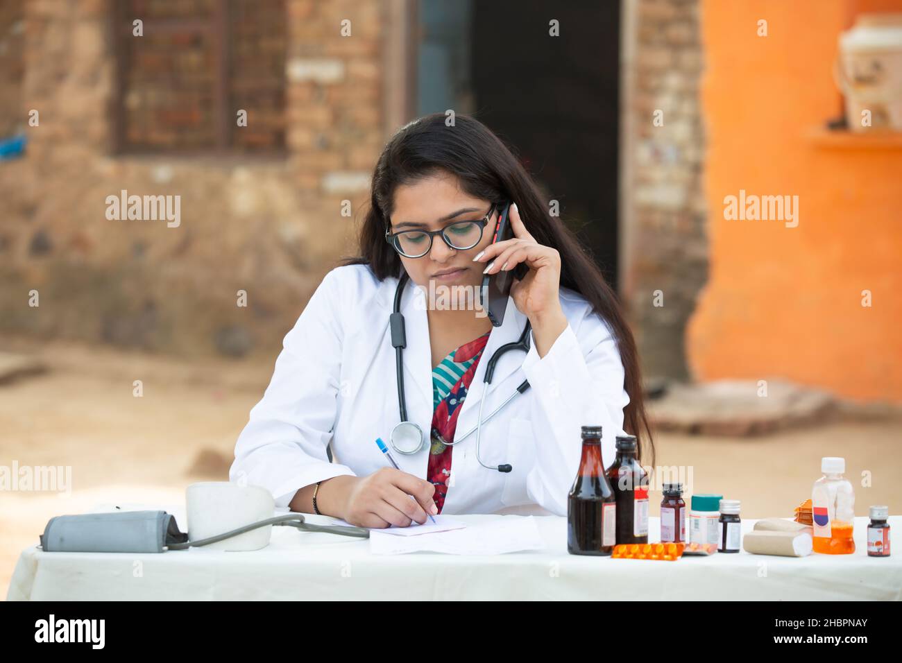 Young Indian Female Doctor writing prescription on paper while talking ...