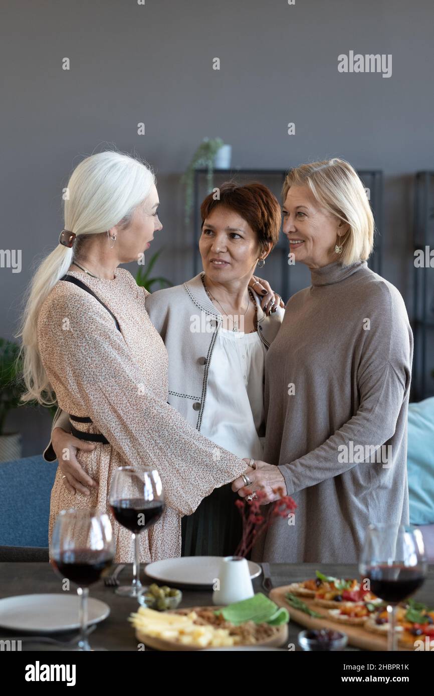 Group of old happy friends embracing and talking to each other during ...