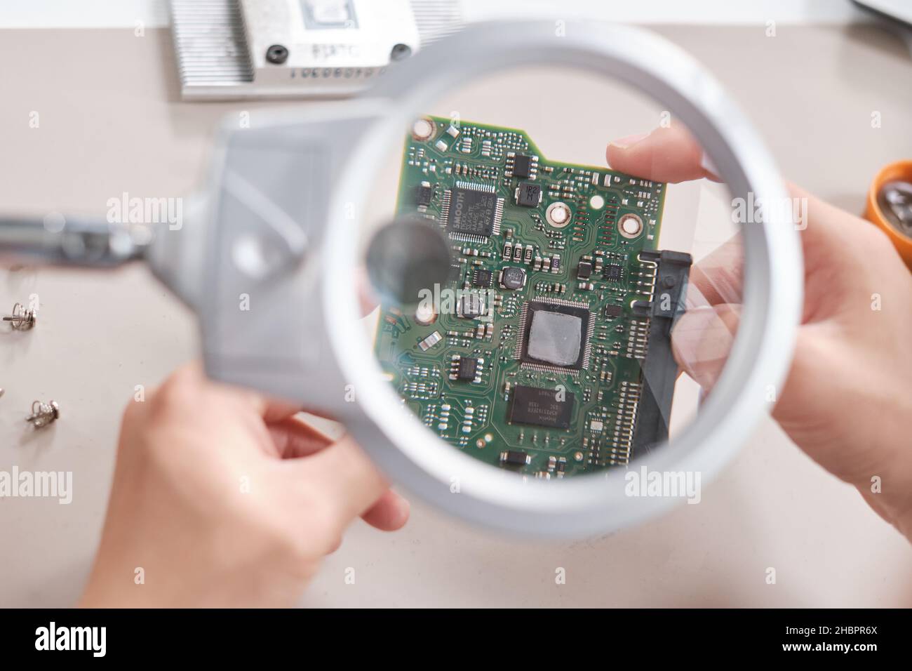Magnifying glass and hands of technician holding circuit board of ...