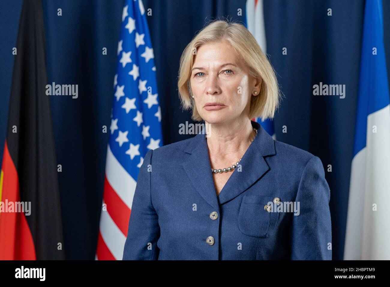 Serious mature female leader in elegant suit standing in front of ...