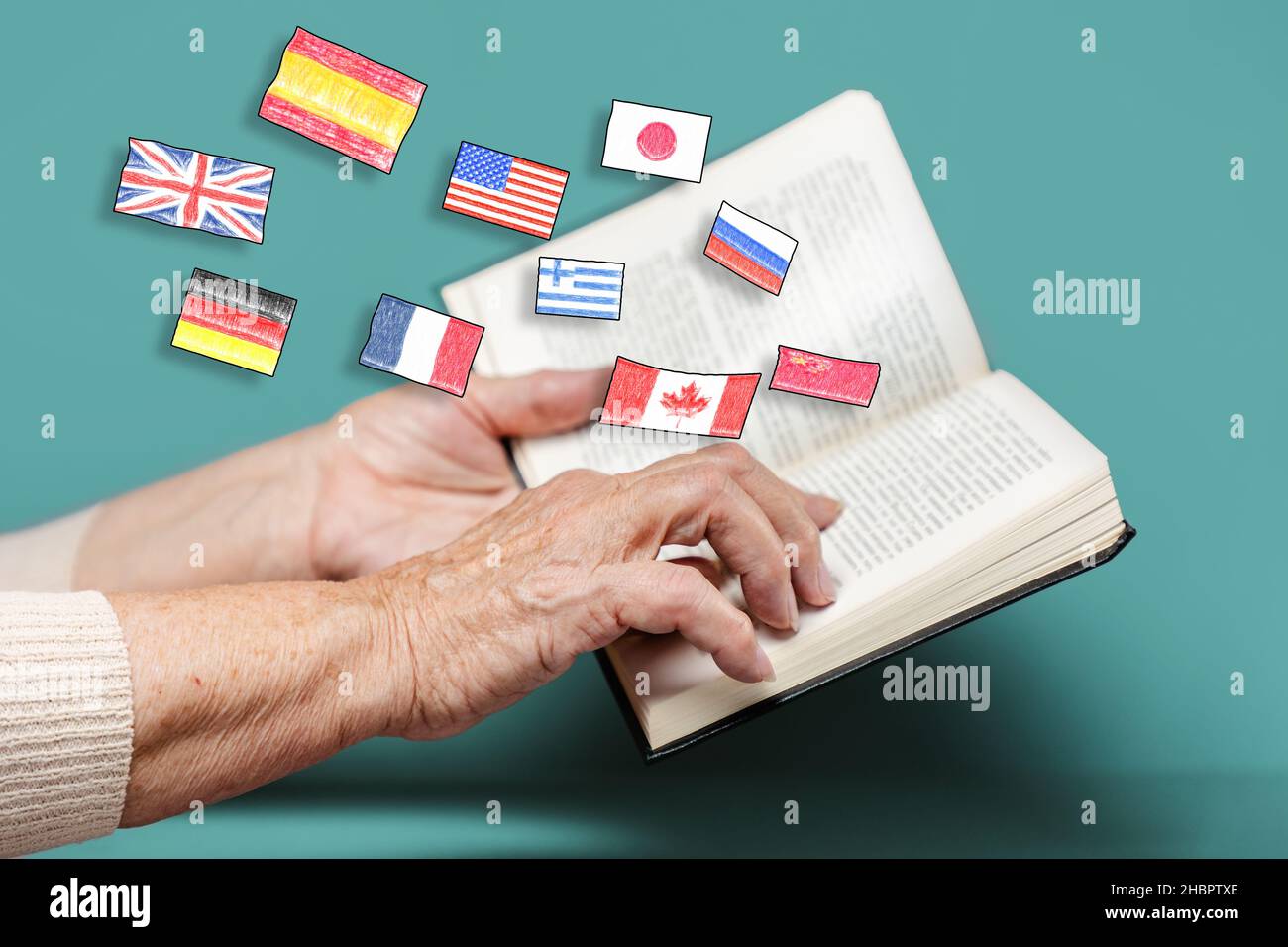 A senior woman reading a book with flags of different countries. Close ...