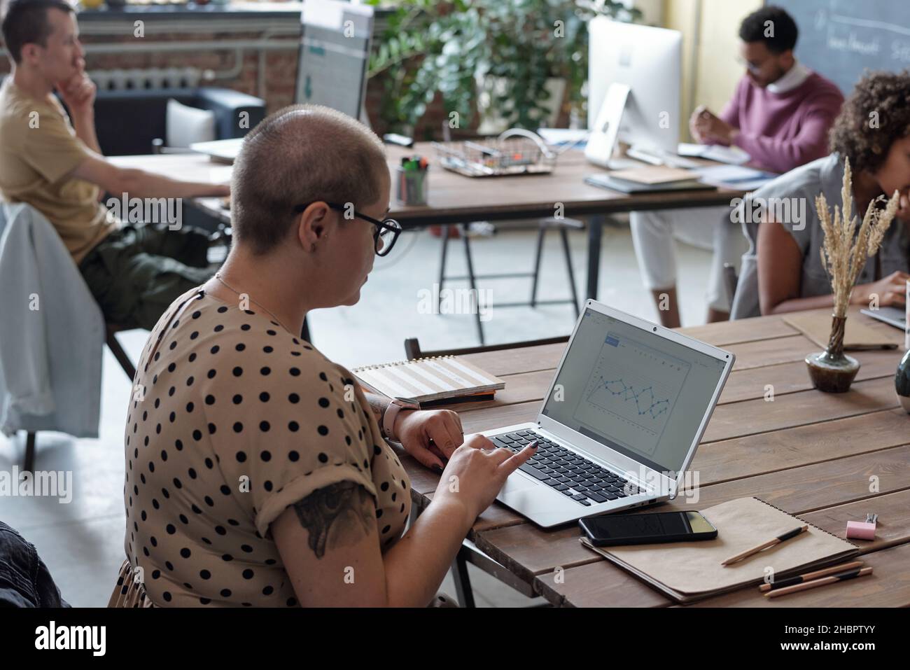 Busy office worker sitting by table in front of laptop and looking at ...