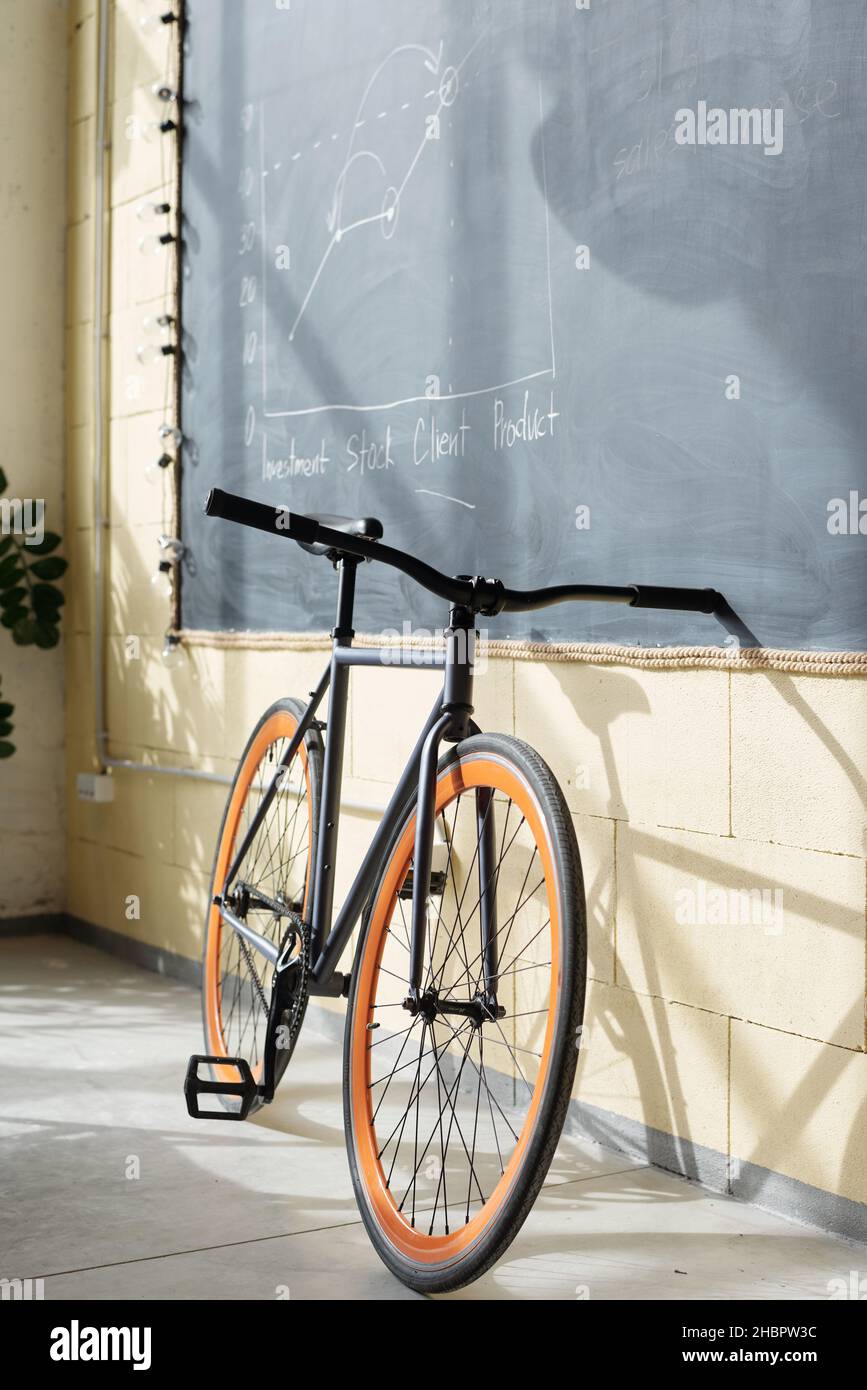Bicycle of white collar worker standing by blackboard with drawn graph ...