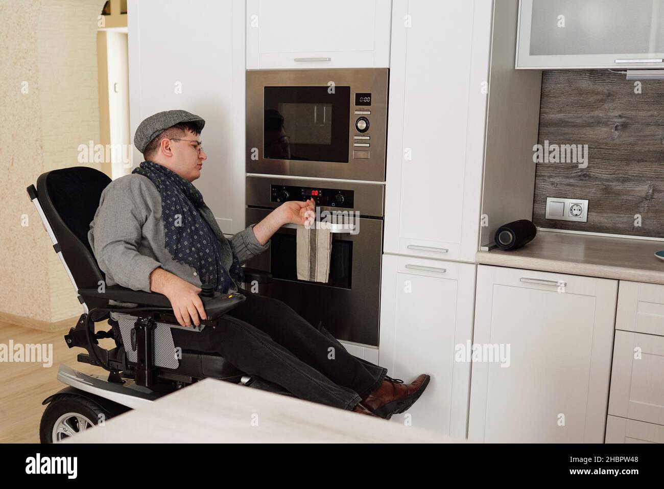 Man with disability checking timer of electric oven while cooking food ...