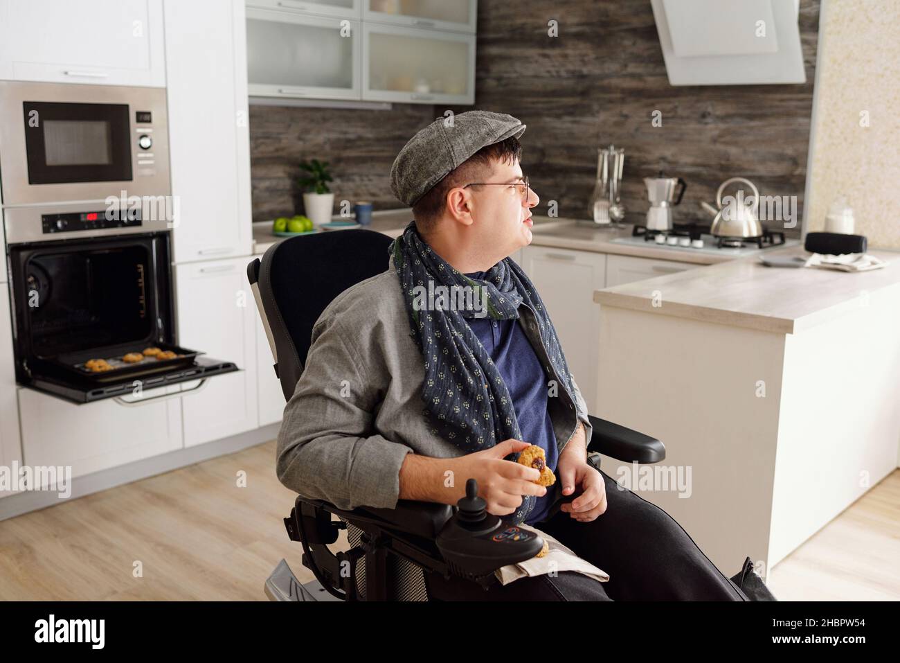 Man in casualwear eating homemade cookie while sitting in wheelchair ...