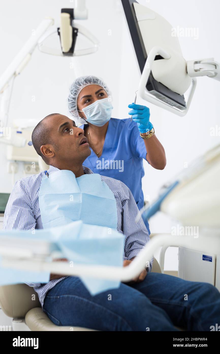 Qualified woman stomatologist pointing at teeth x-ray image on computer ...