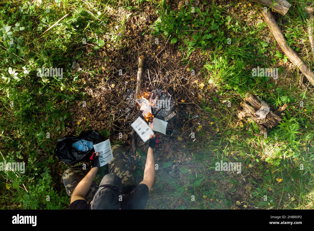 Man burning paper in a campfire, top view Stock Photo - Alamy