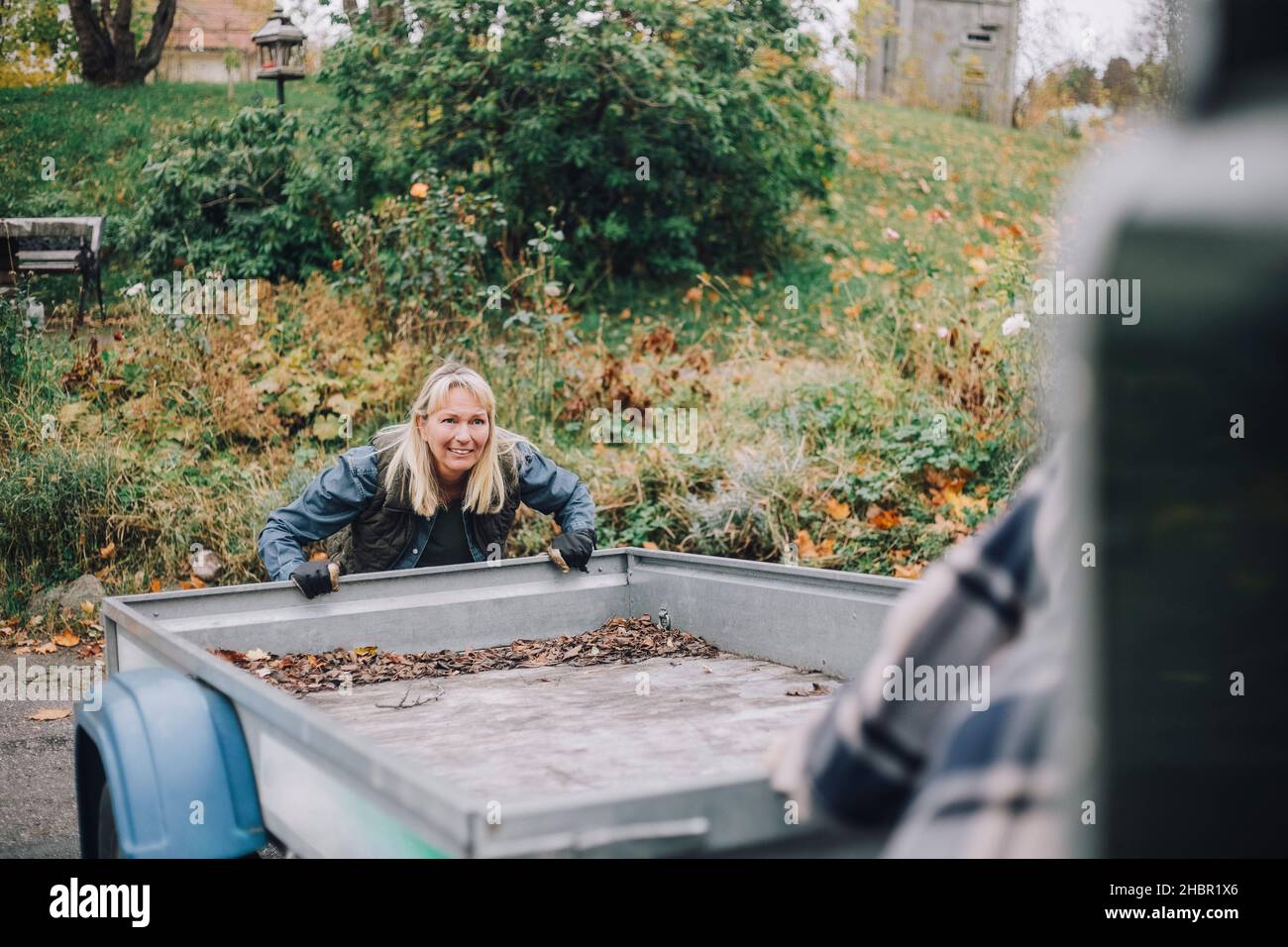Mature woman pushing vehicle trailer with male friend on driveway Stock ...