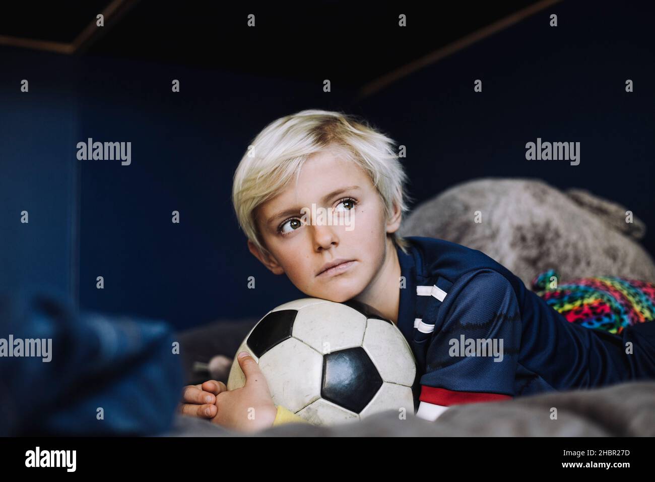 Blond boy day dreaming in bedroom at home Stock Photo - Alamy