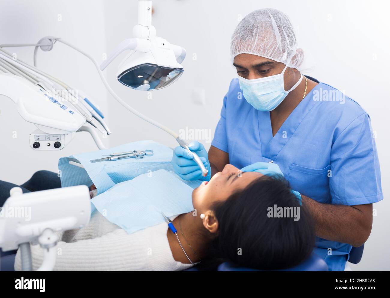 Professional african american dentist performing teeth treatment to ...