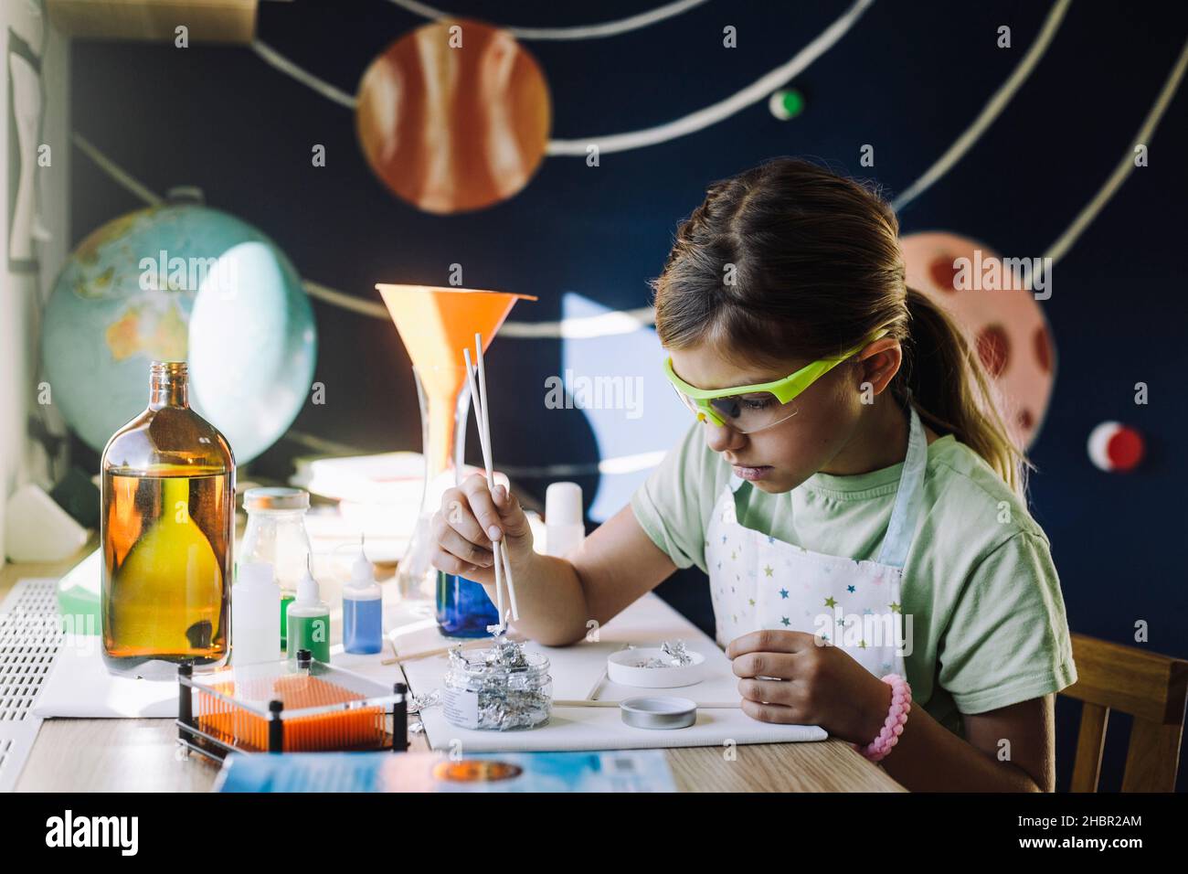 Girl doing scientific experiment at table Stock Photo - Alamy