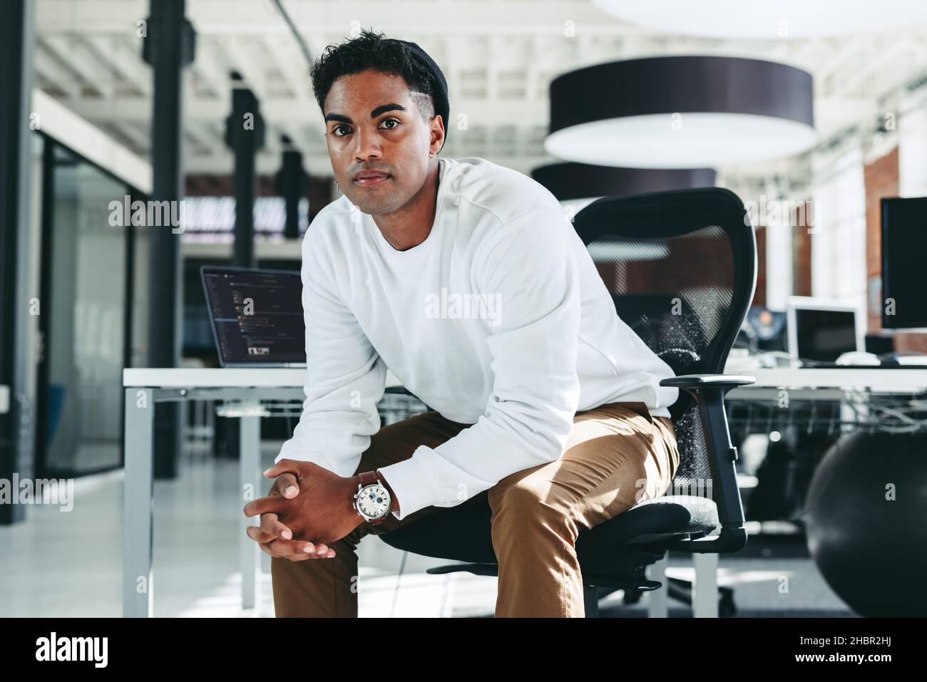 Digital developer looking at the camera in a modern workplace ...