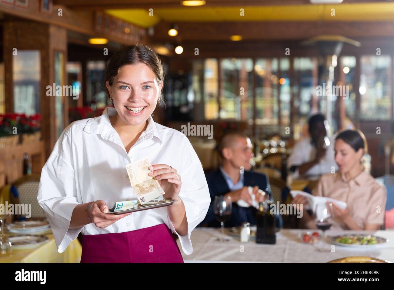 Happy cheerful attractive woman waiter with good tip in restaurant ...