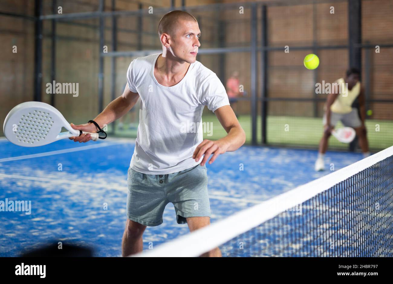 Portrait of concentrated paddle tennis player preparing to hit forehand ...