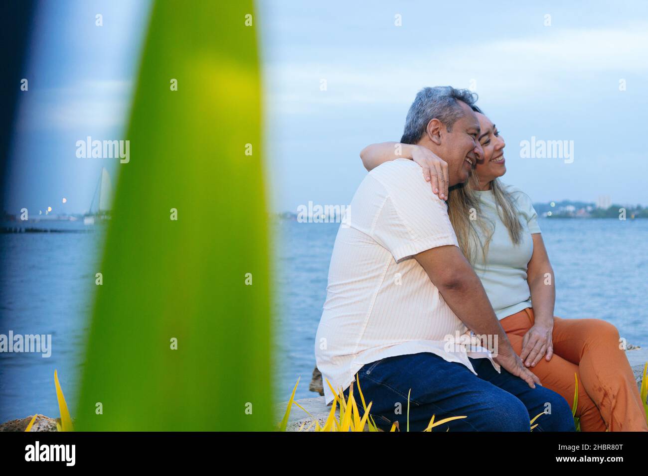 Latin couple is sitting in the park hugging each other Stock Photo - Alamy