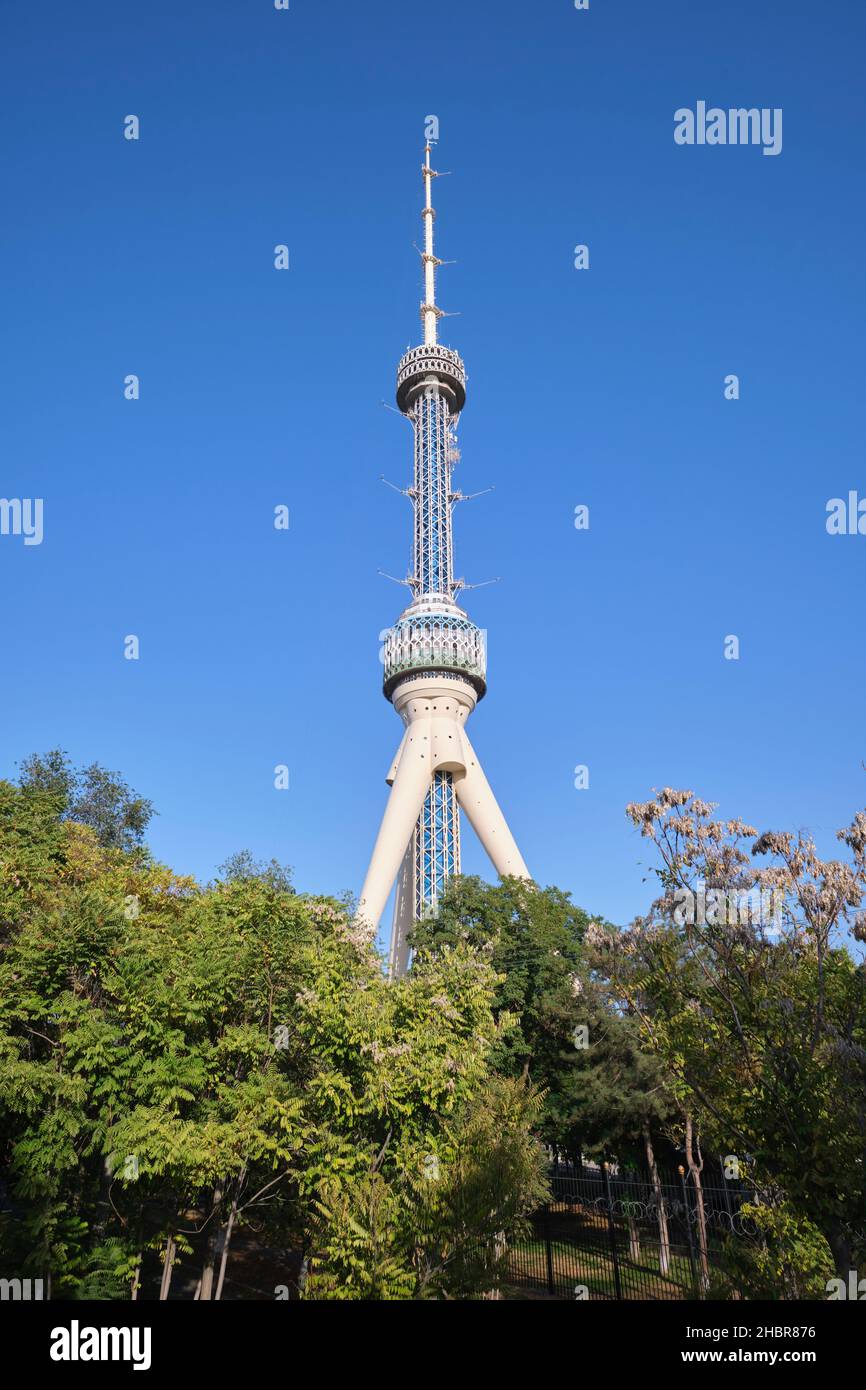 A view of the Tashkent Television Tower with green trees and a blue sky ...