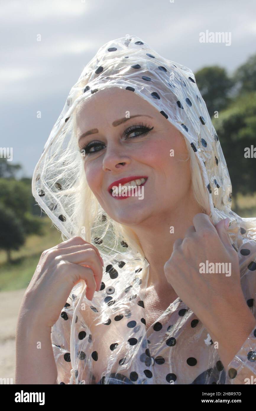 Pretty glamorous young woman dressed in retro 1950s swimsuit worn under a see through plastic ...