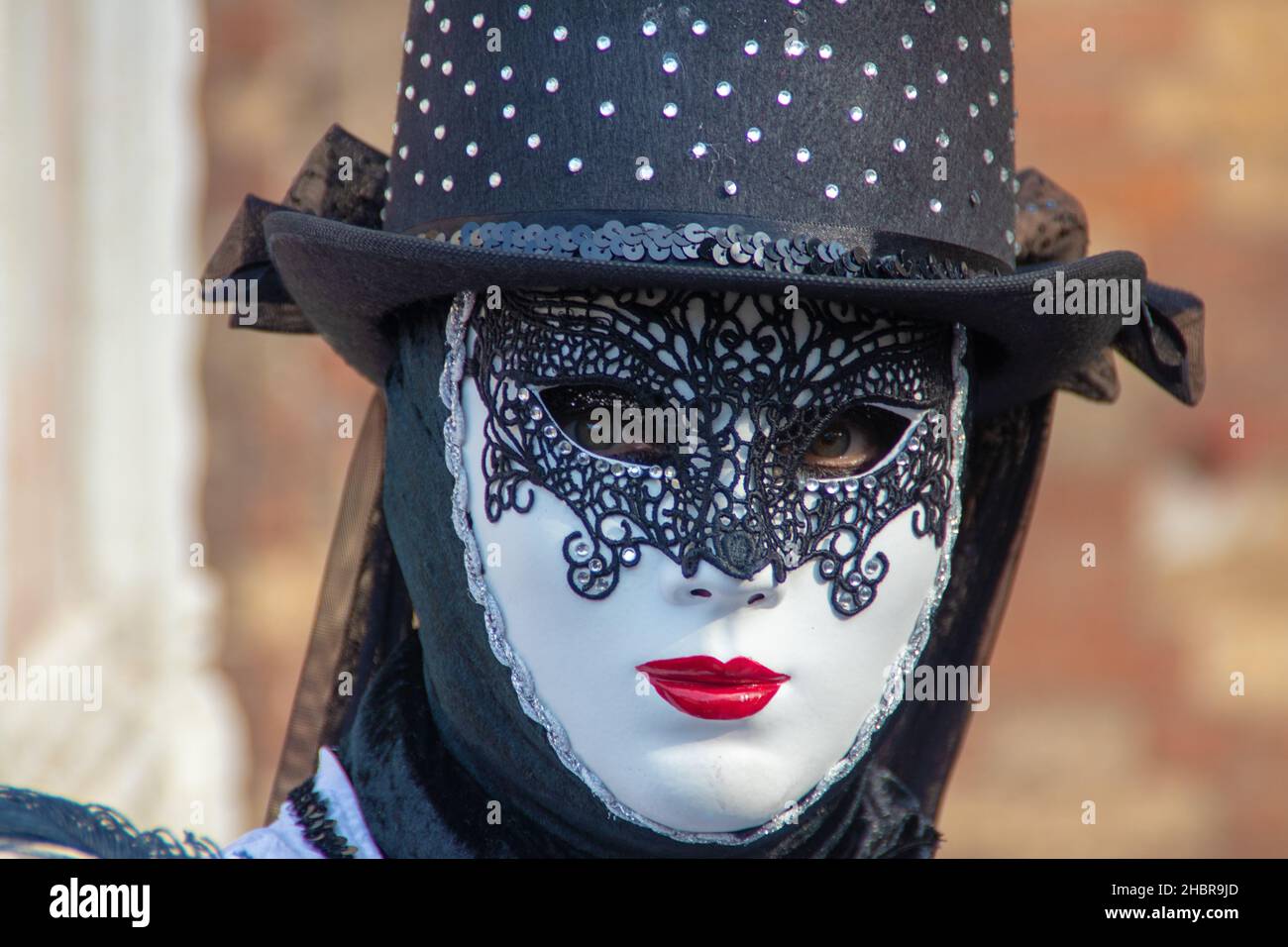 VENEZIA, ITALY - Mar 05, 2019: A masked woman in a black beautiful hat ...