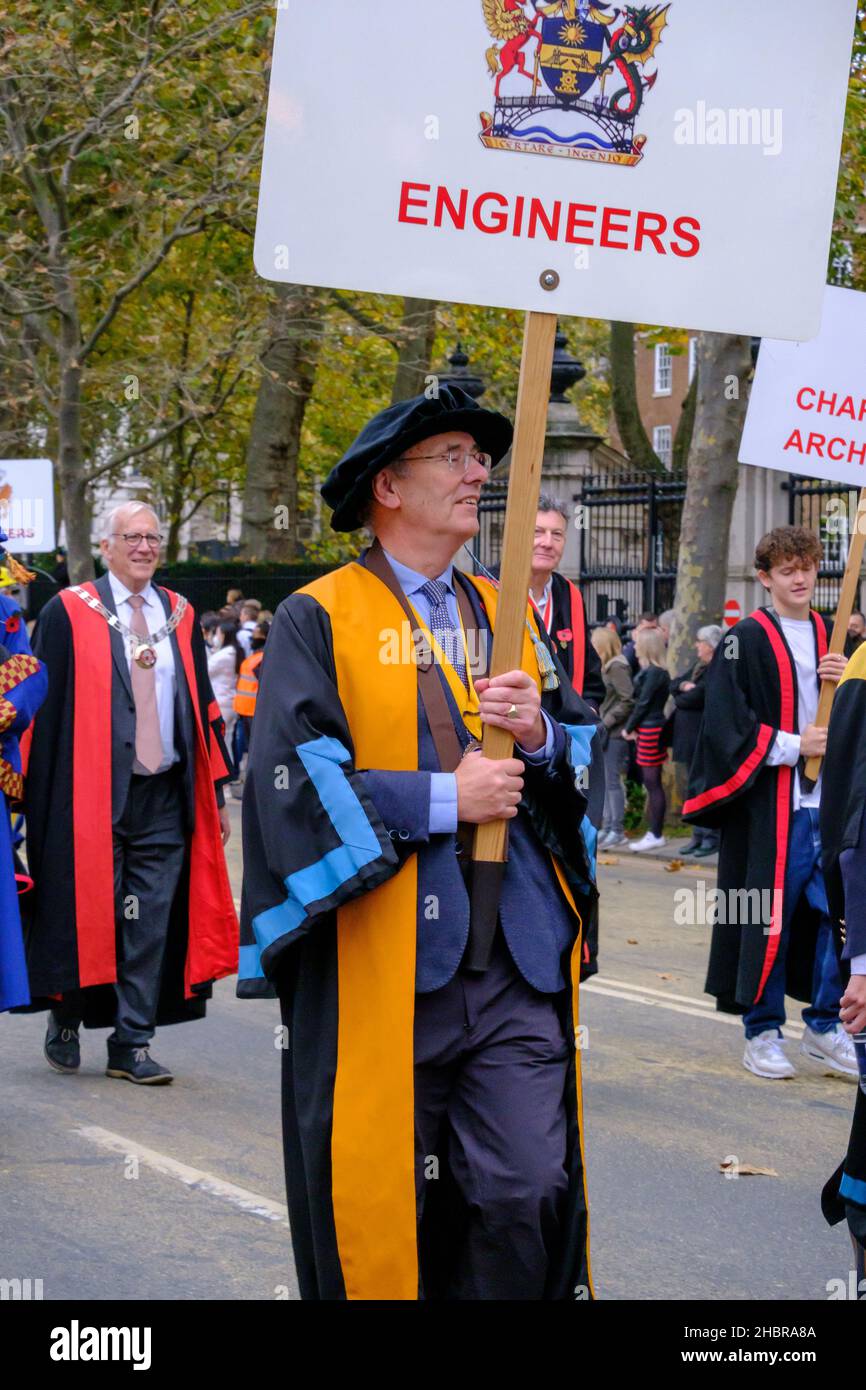 A man in ceremonial robes holds a sign for Engineers as he marches with ...