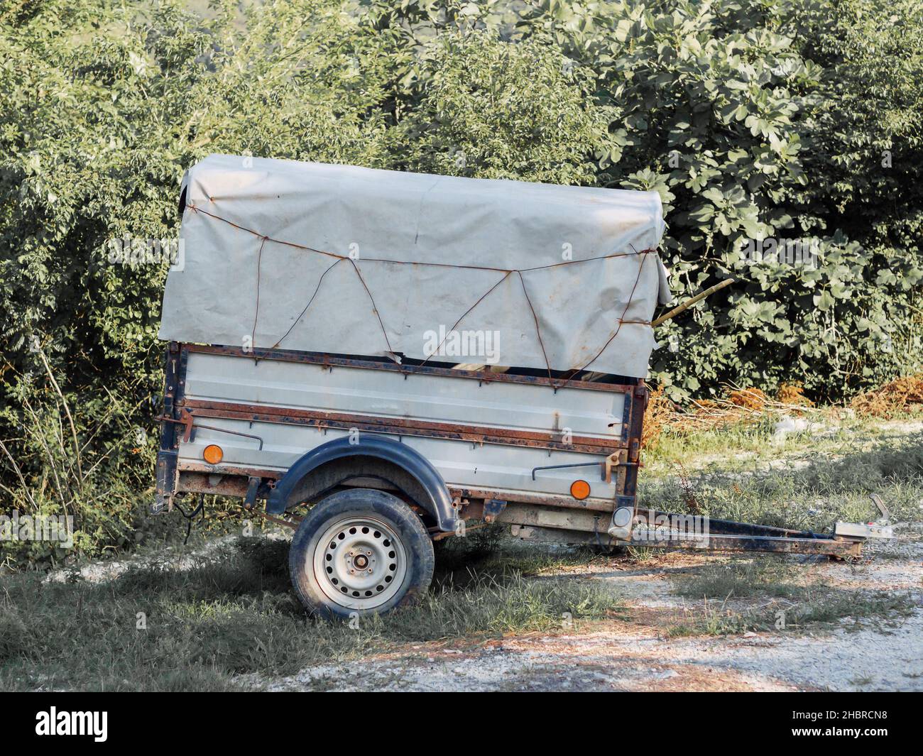 A two-wheeled trailer with canopy stands against the background of ...