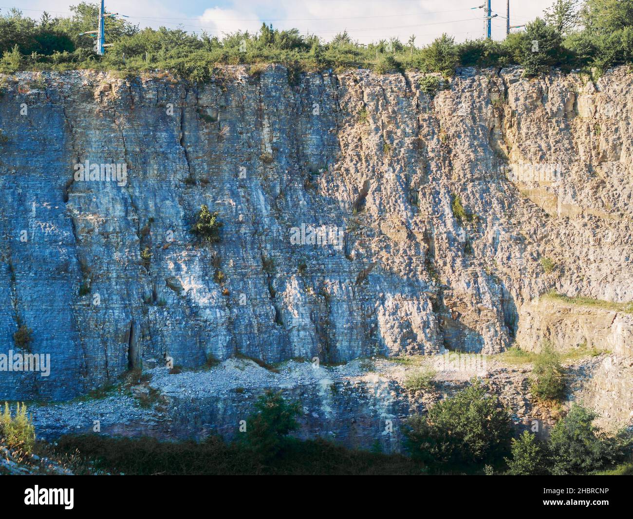 A valley with steep rocky cliff with green vegetation at the top and ...