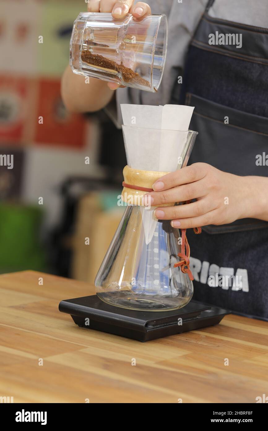 A vertical shot of a barista pouring coffee in a pour-over style ...