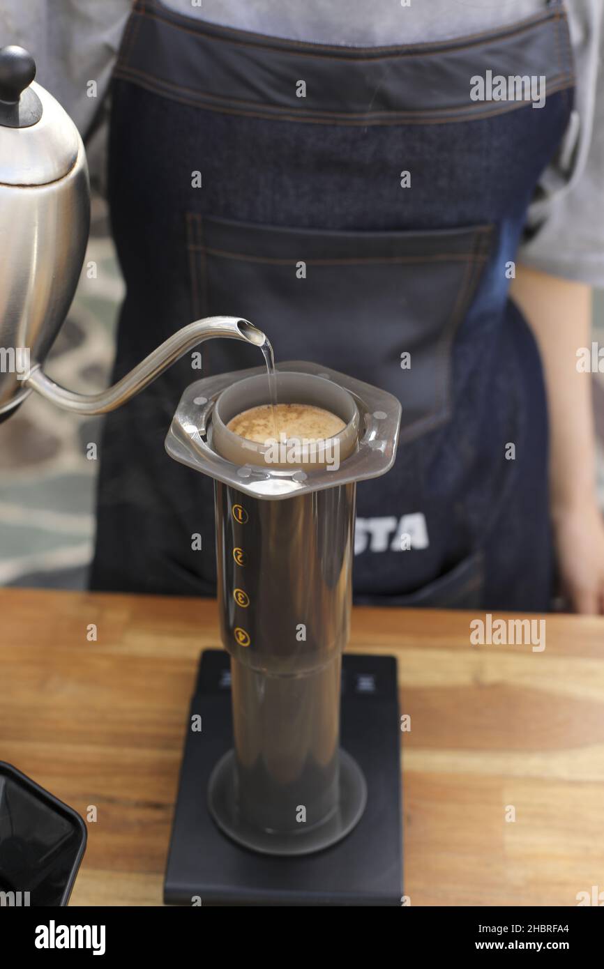 A vertical shot of a barista pouring water in a manual coffeemaker on a ...