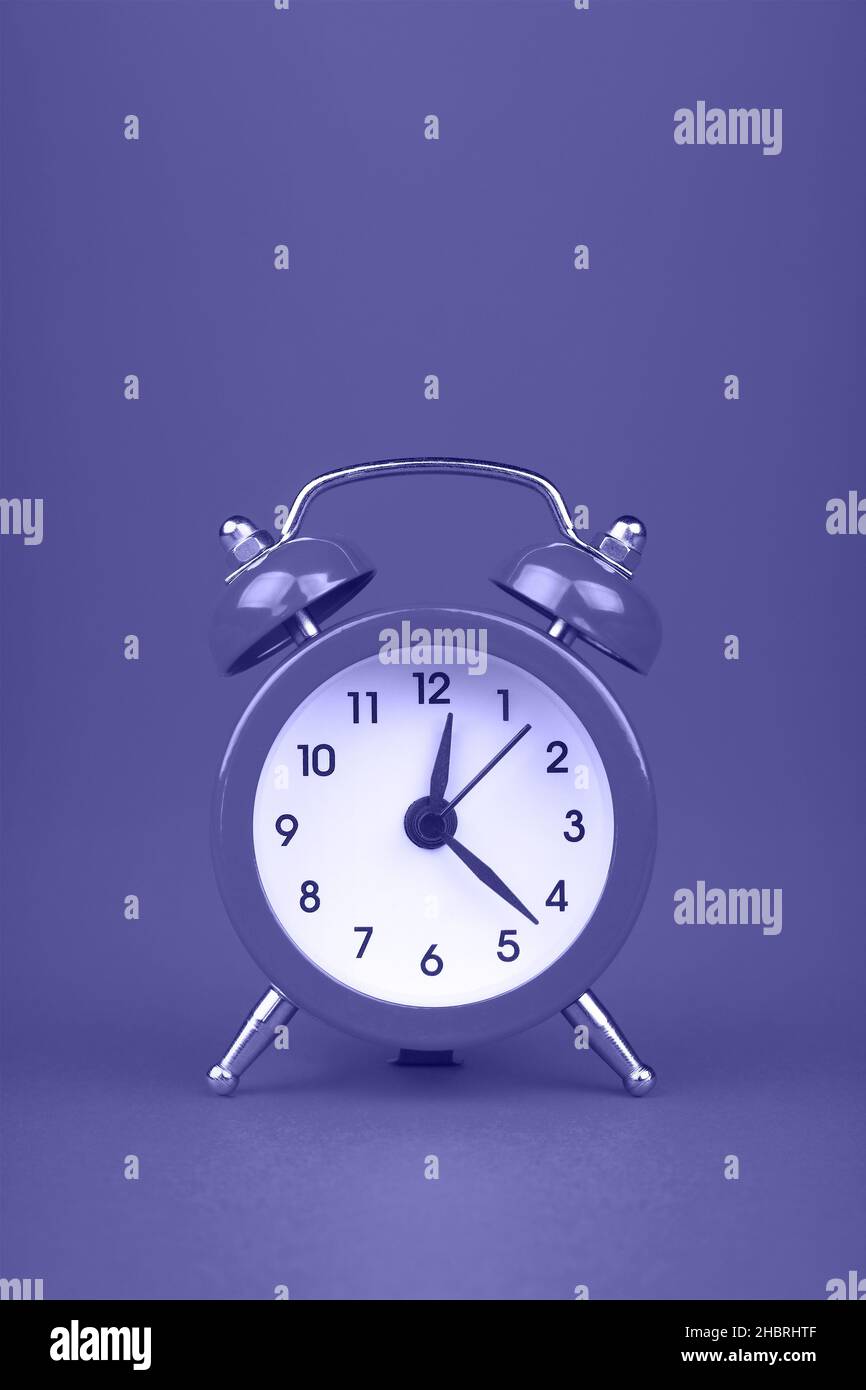 Close up one small purple metal twin bell retro alarm clock over violet ...