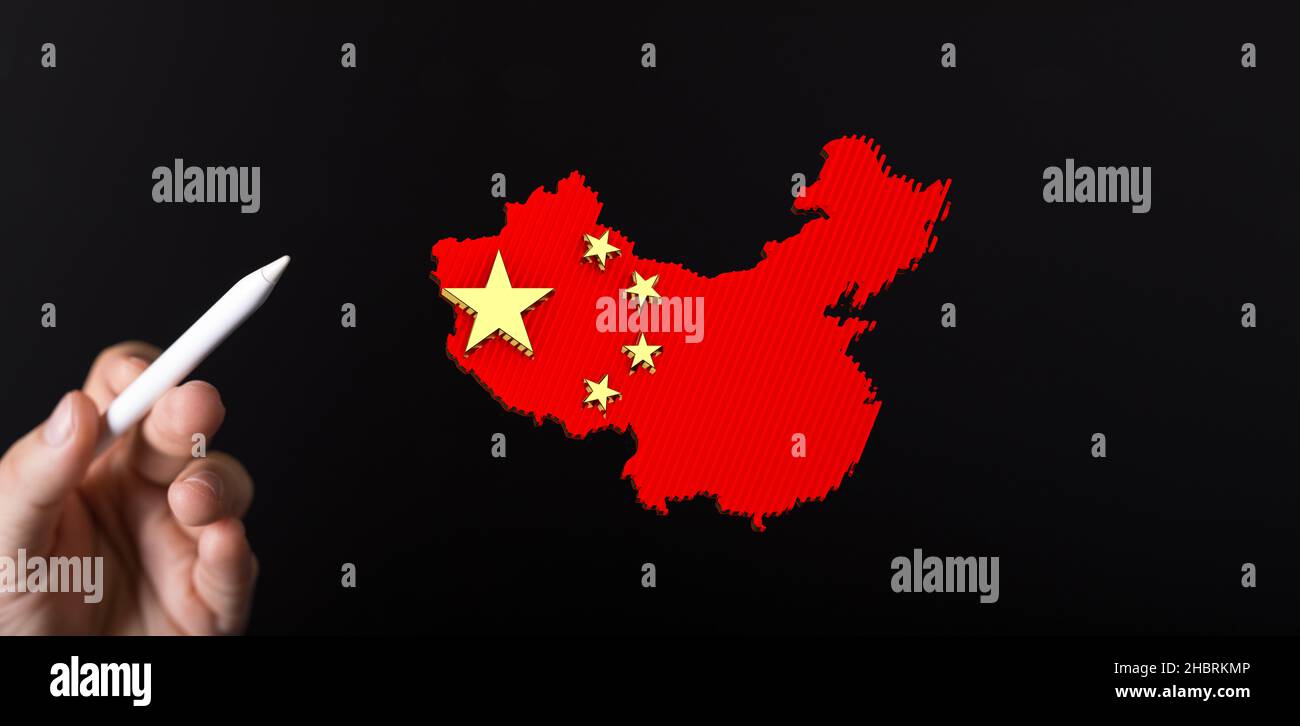 A hand holding a pen on the background of the national flag of China in ...