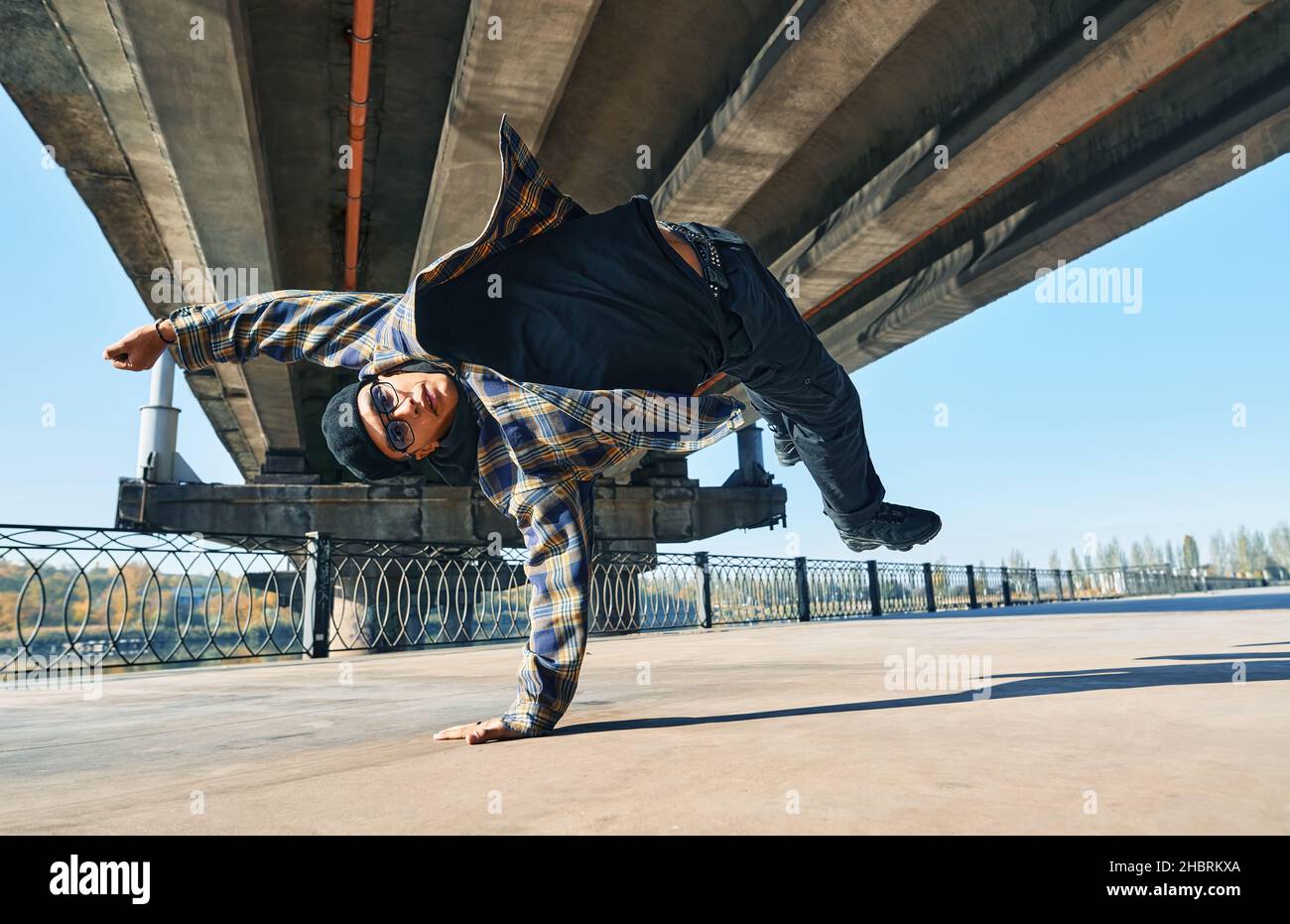 Young man break dancer dancing on urban background performing acrobatic ...