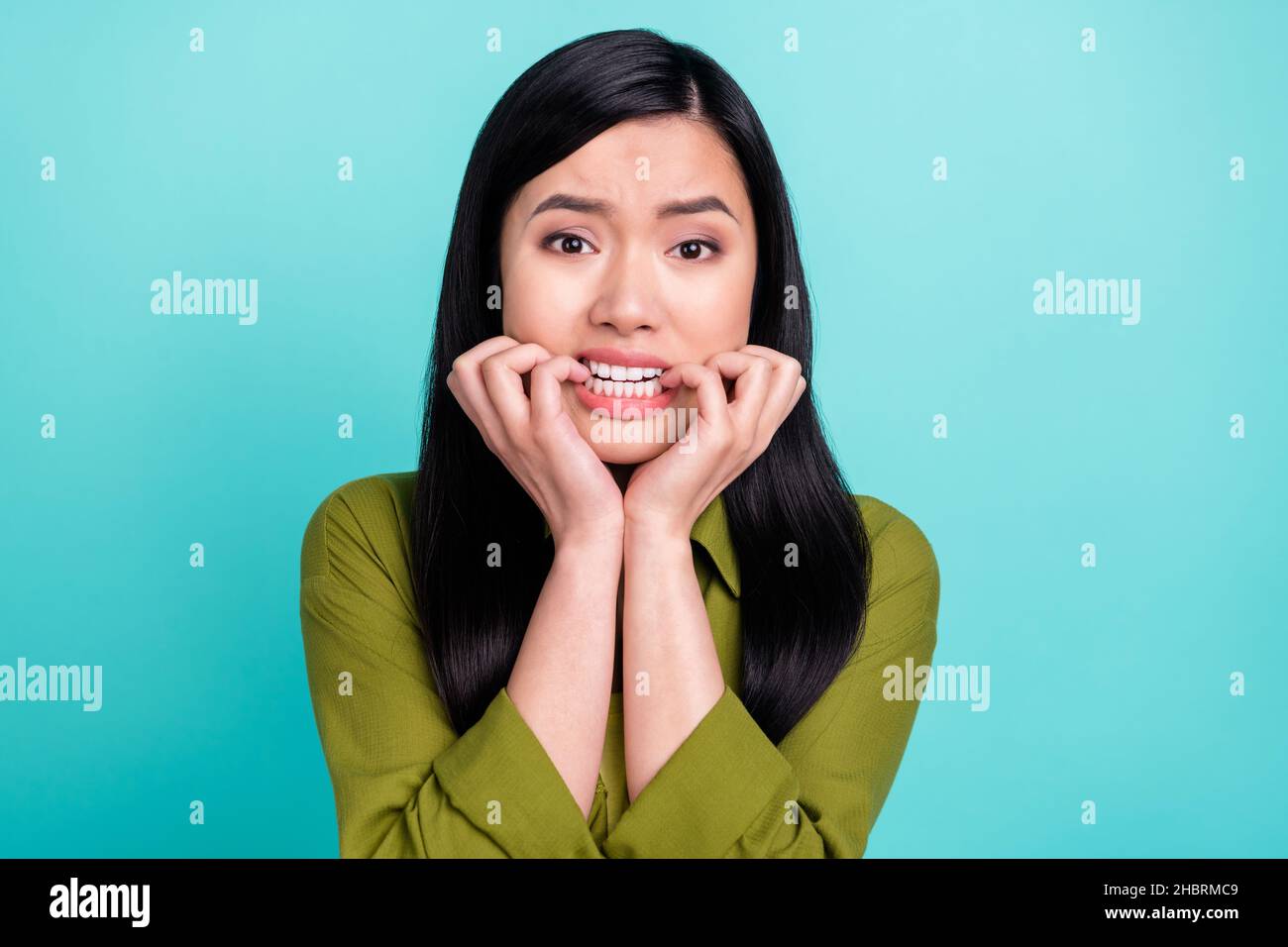 Photo of young asian girl frightened scared bite teeth fingers mistake ...