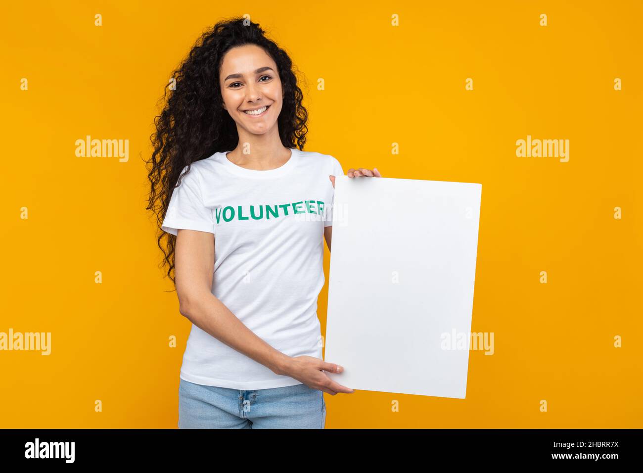 Female Volunteer Holding Empty Paper Board Over Yellow Background Stock ...