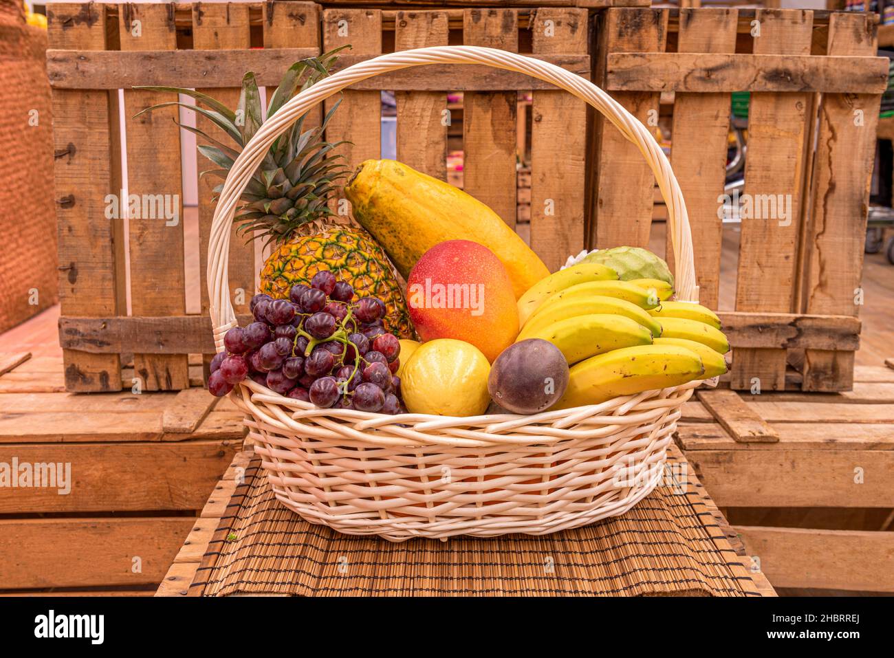 Unvarnished wicker basket filled with fresh fruits, bananas, mango ...